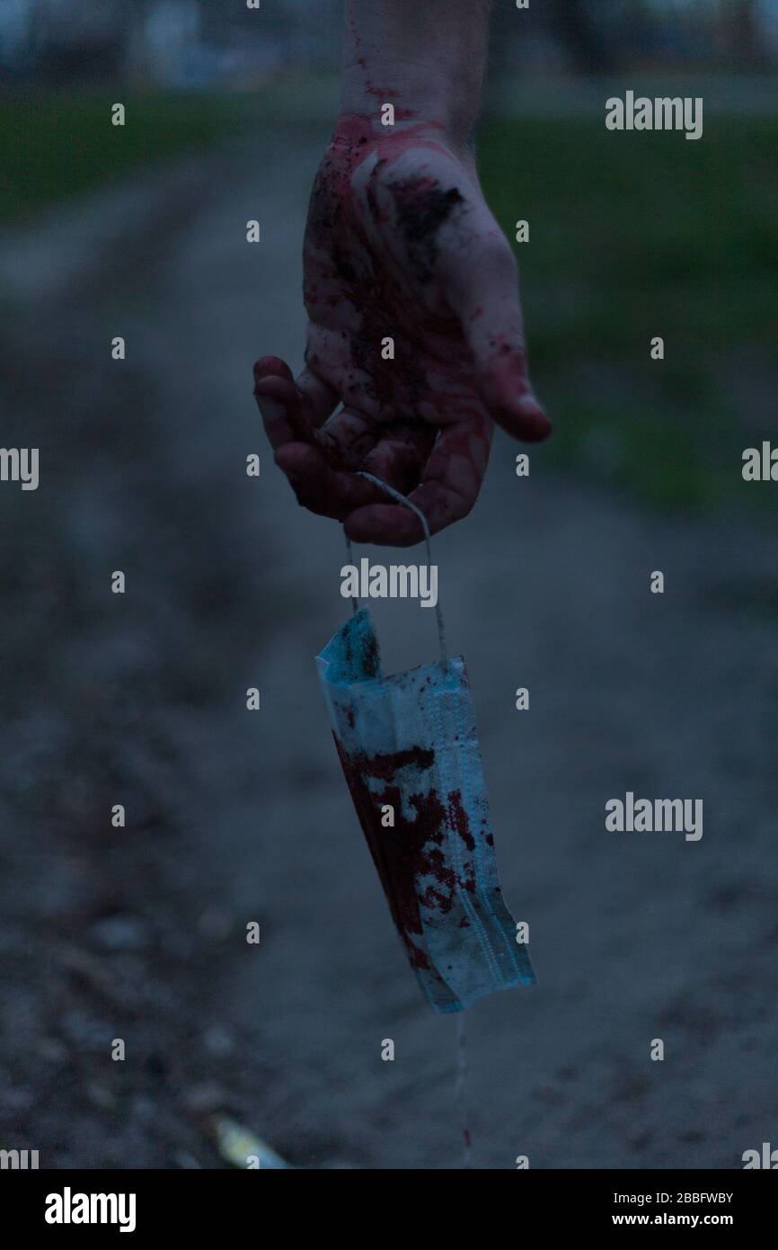 A medical bloodied mask lies on the ground with a bloody hand reaching ...
