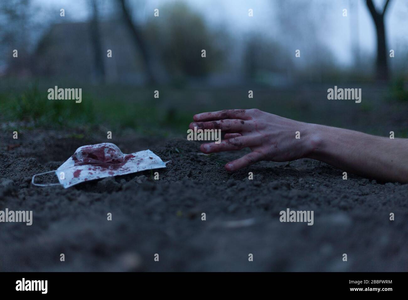 A medical bloodied mask lies on the ground with a bloody hand reaching ...