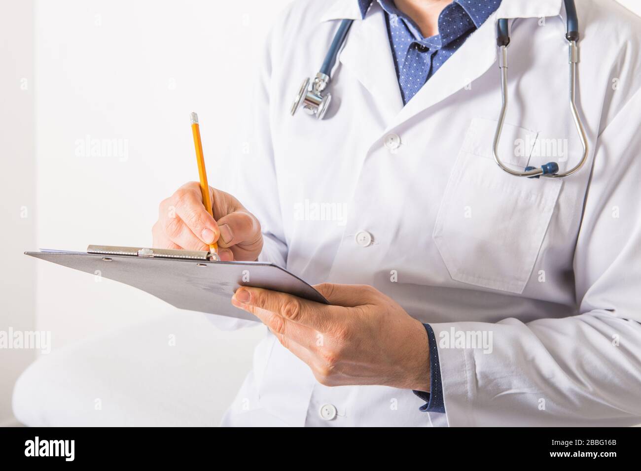 Doctor with stethoscope writing RX prescription on clipboard on white ...