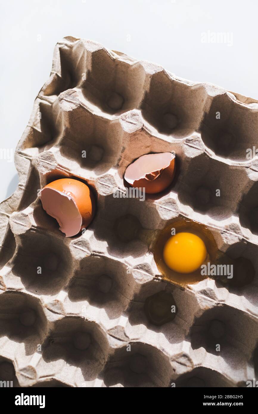 Yellow yolk and cracked eggshell in carton egg box. Easter vertical ...