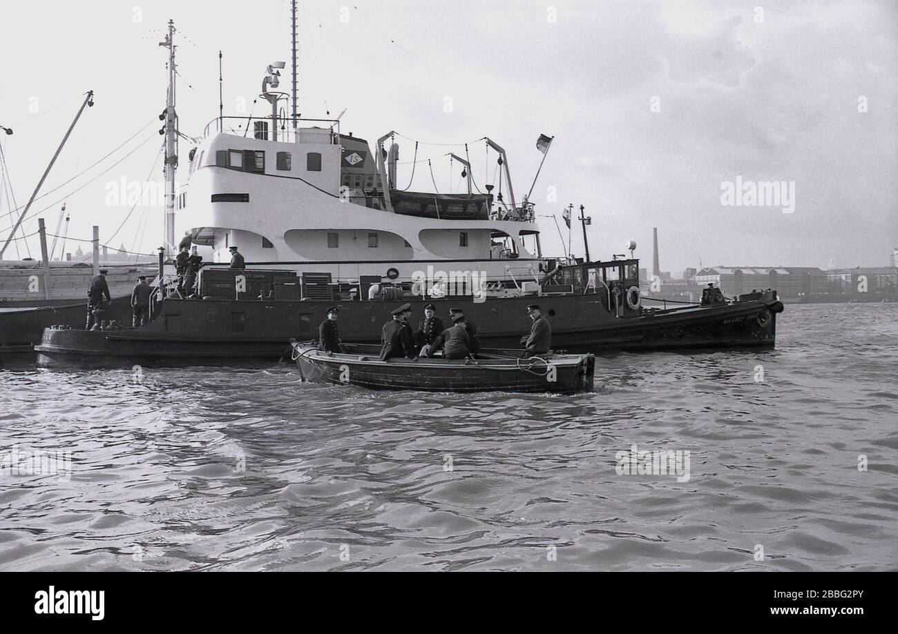 1960s, historical, Woolwich and Port of London workers in boats help a ...