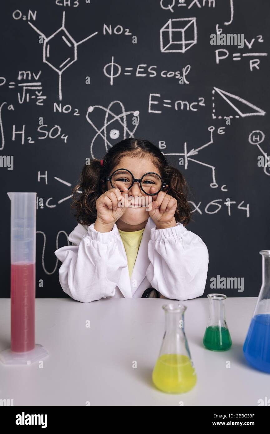 funny little scientist girl in lab coat joking with her glasses, on ...