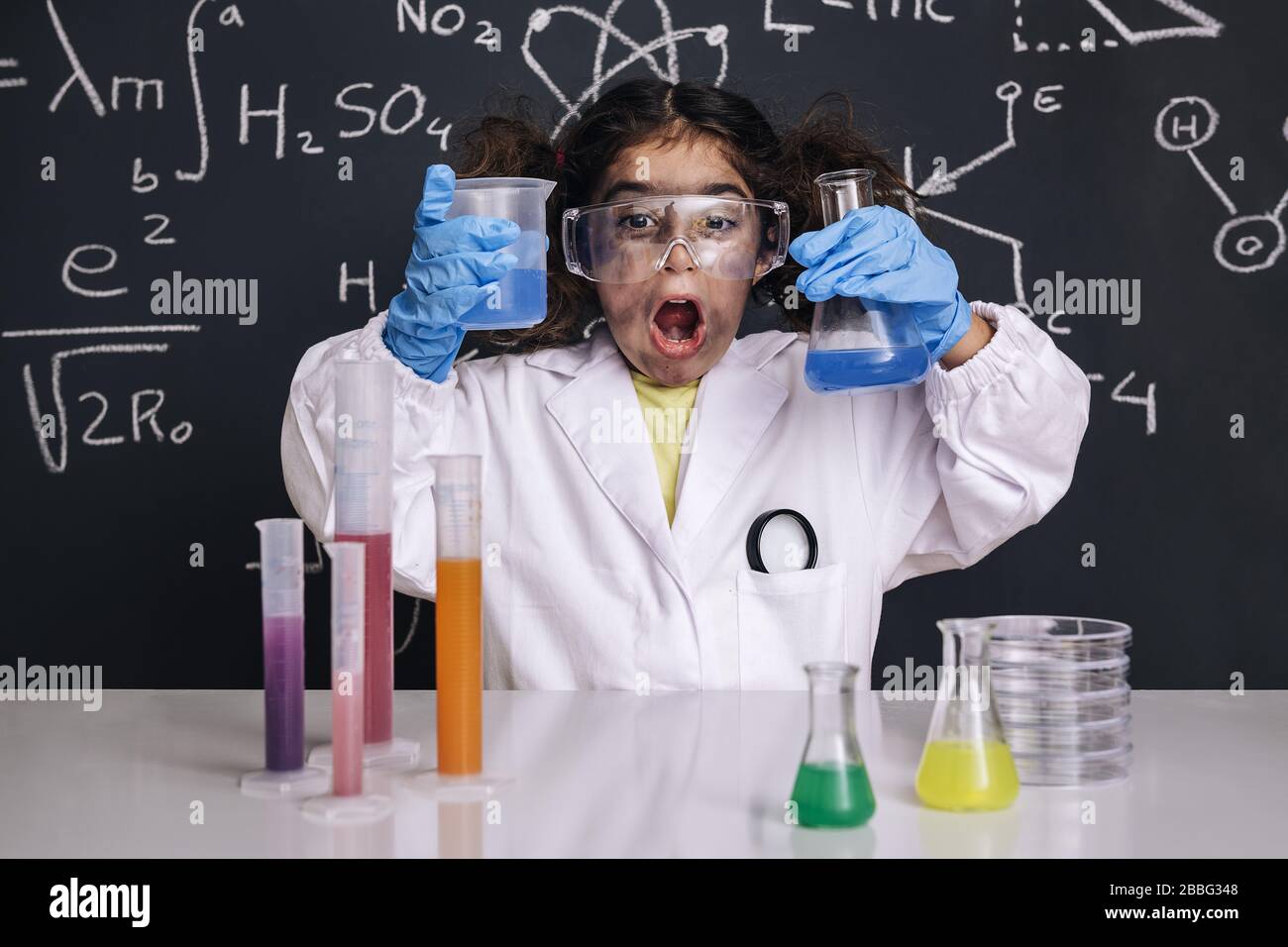 funny scientist child with gloves and goggles in lab coat with chemical ...