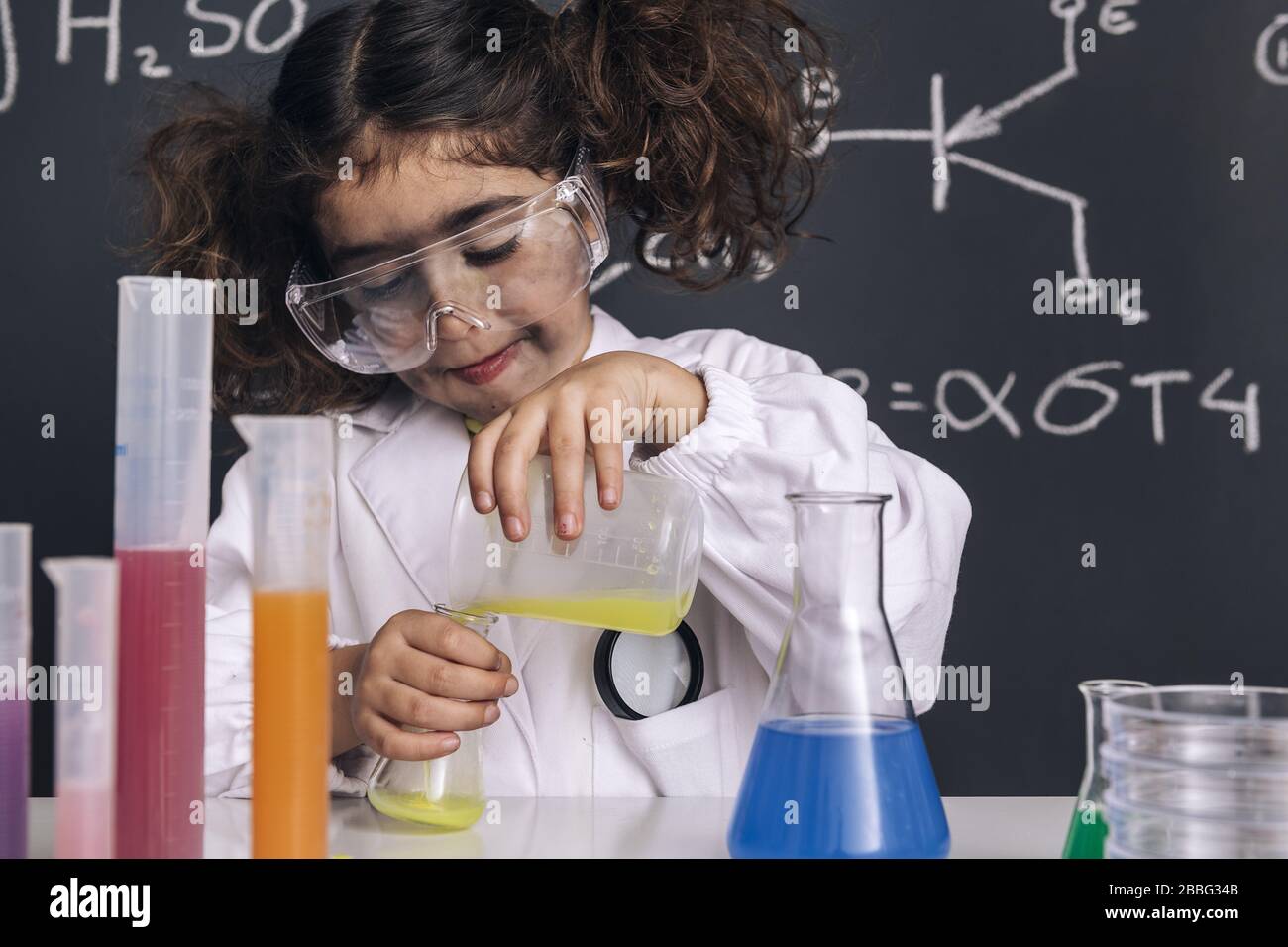 funny scientist child with goggles and gloves in lab coat mixing ...