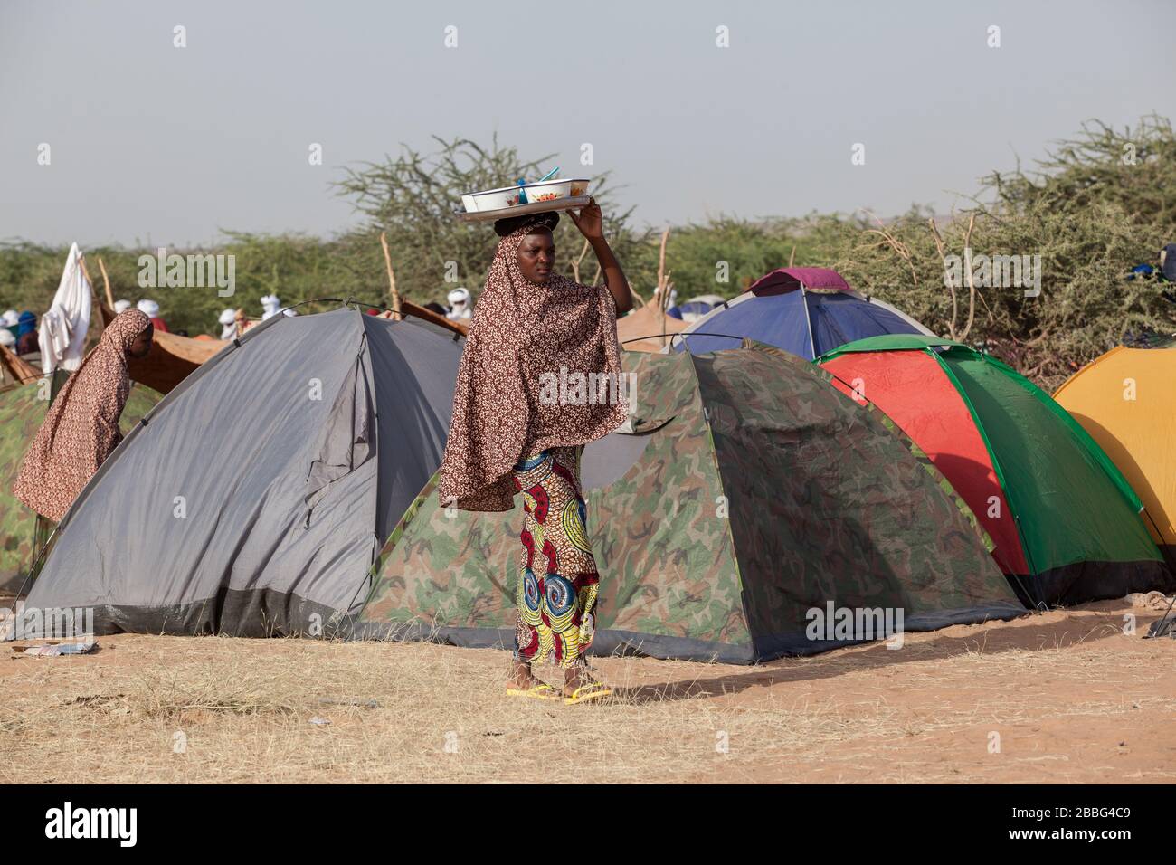 Ingall, Niger: woman in traditional clothing carry food in tent camp in ...