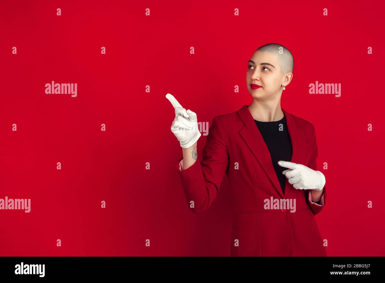 Pointing, showing. Portrait of young caucasian bald woman isolated on ...