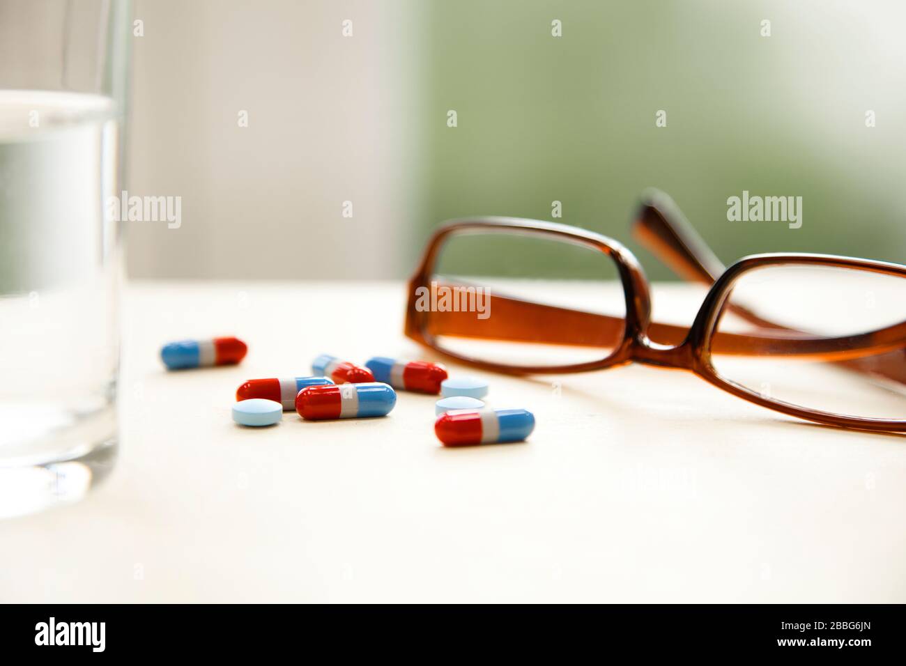 Medication next to a pair of glasses and a glass of water Stock Photo ...