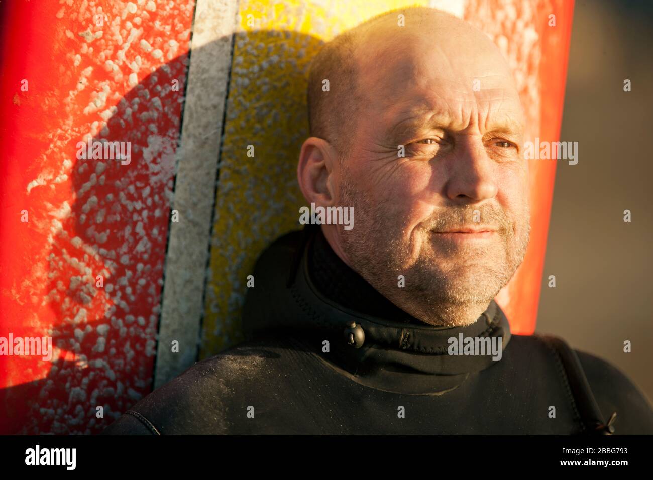 Content mid adult man standing with his surfboard in the sunshine Stock ...