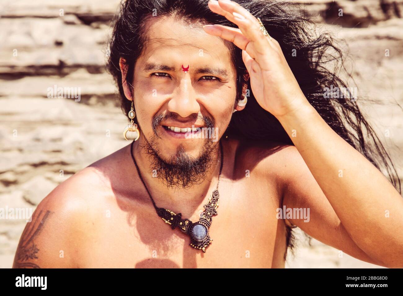 Outdoor portrait of fashionable long hair young man with bindi and ...