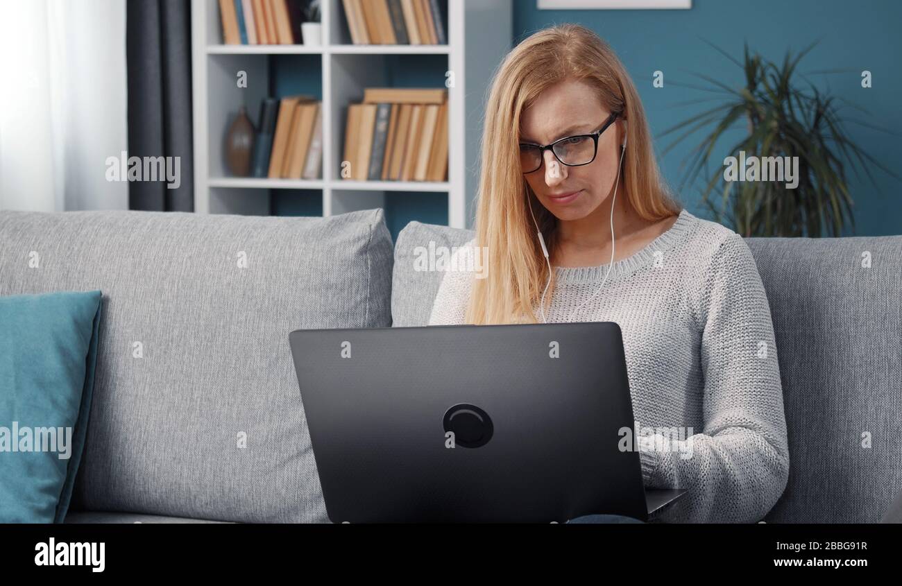 Lady using laptop on couch Stock Photo - Alamy