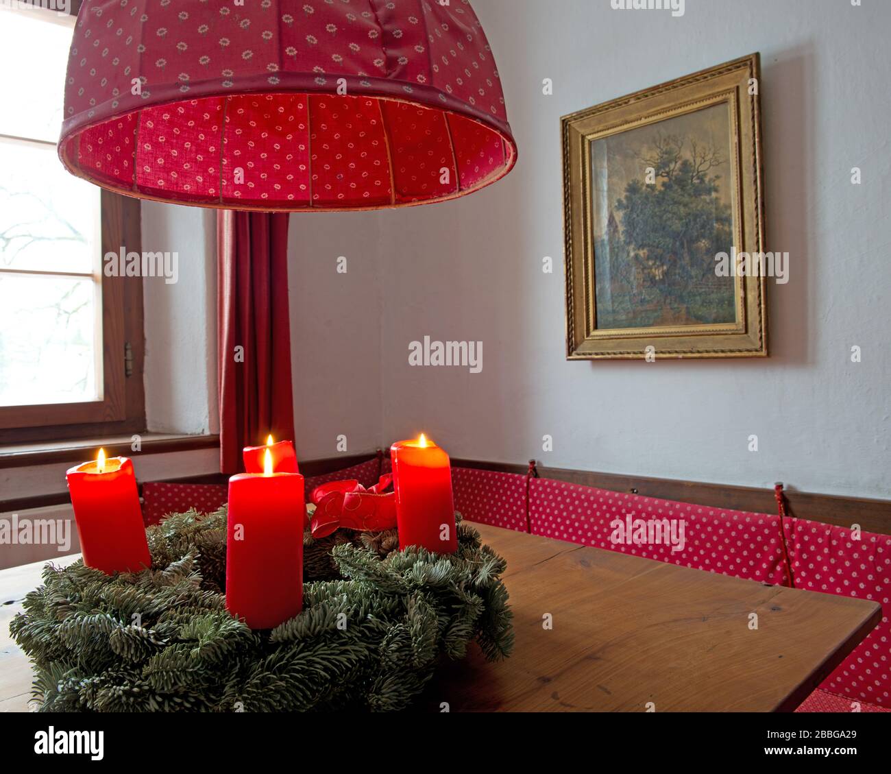 advent wreath on wooden table with four red burning candles, window in ...
