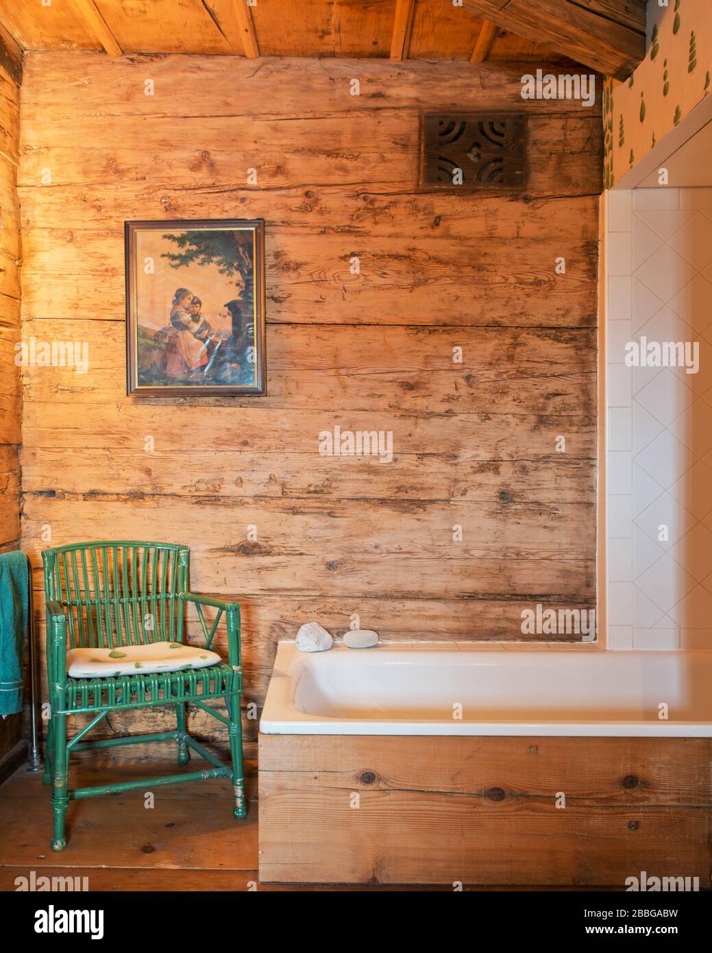 wood clad bathroom with bathtub, green chair and painting Stock Photo ...