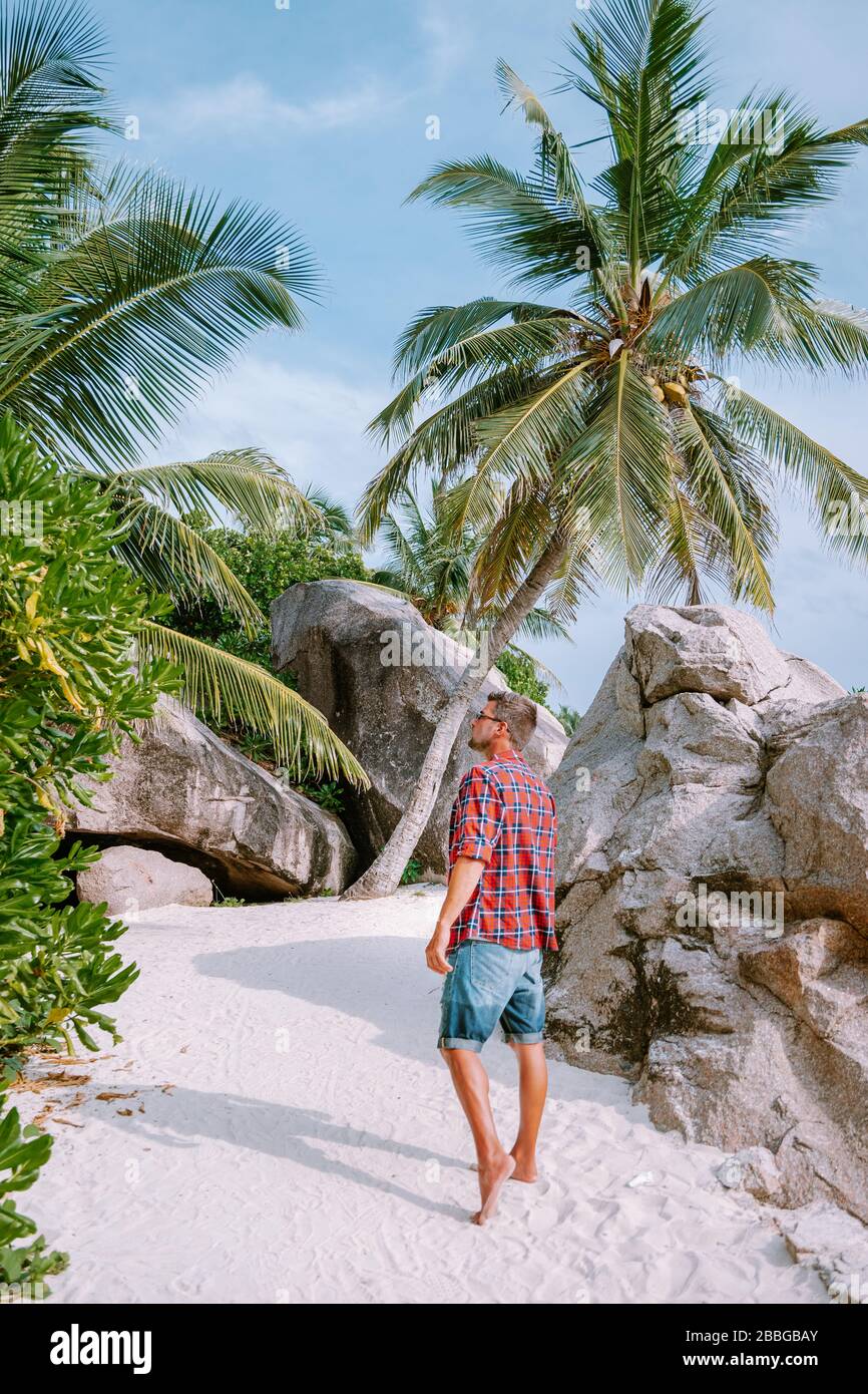 La Digue Seychelles, young men walking at the white beach with clear ...