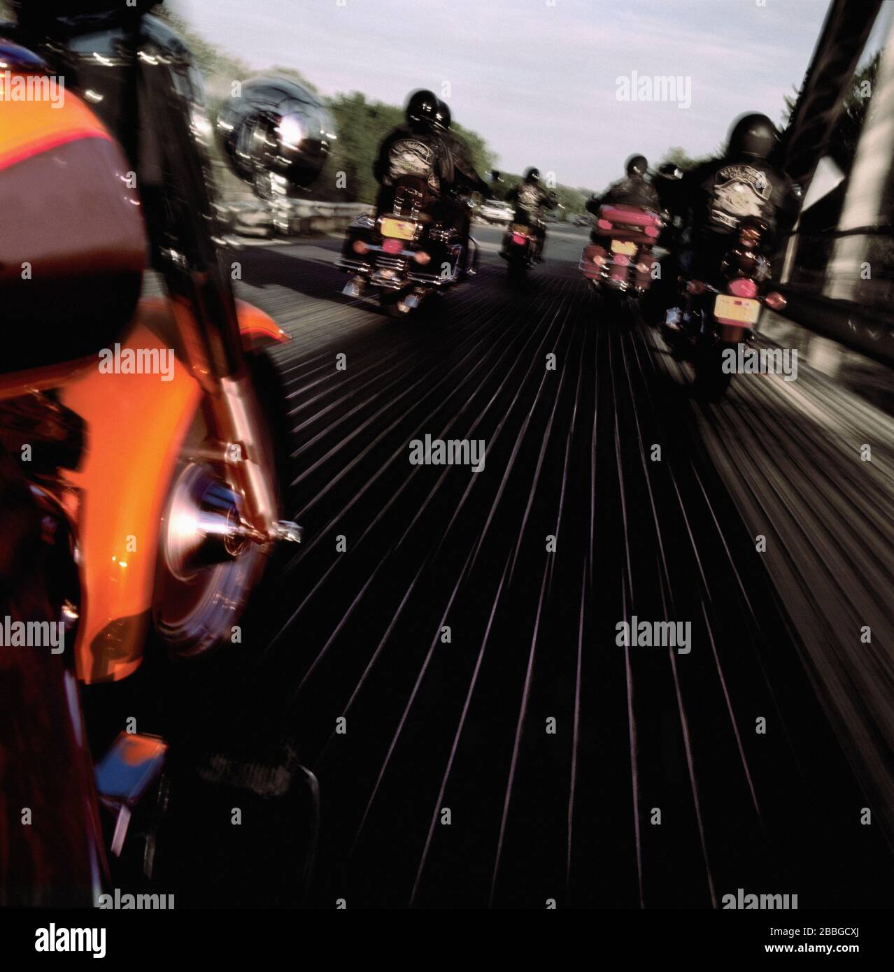 Rear view of a group of people riding their motorbikes on a bridge ...