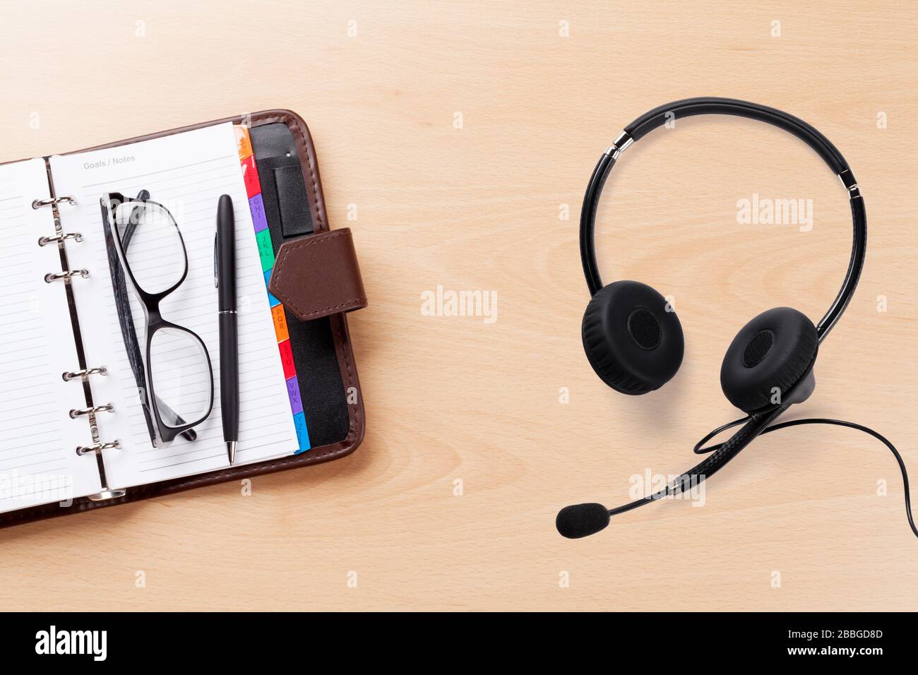 Office wooden workplace backdrop with supplies and headset. Remote call ...