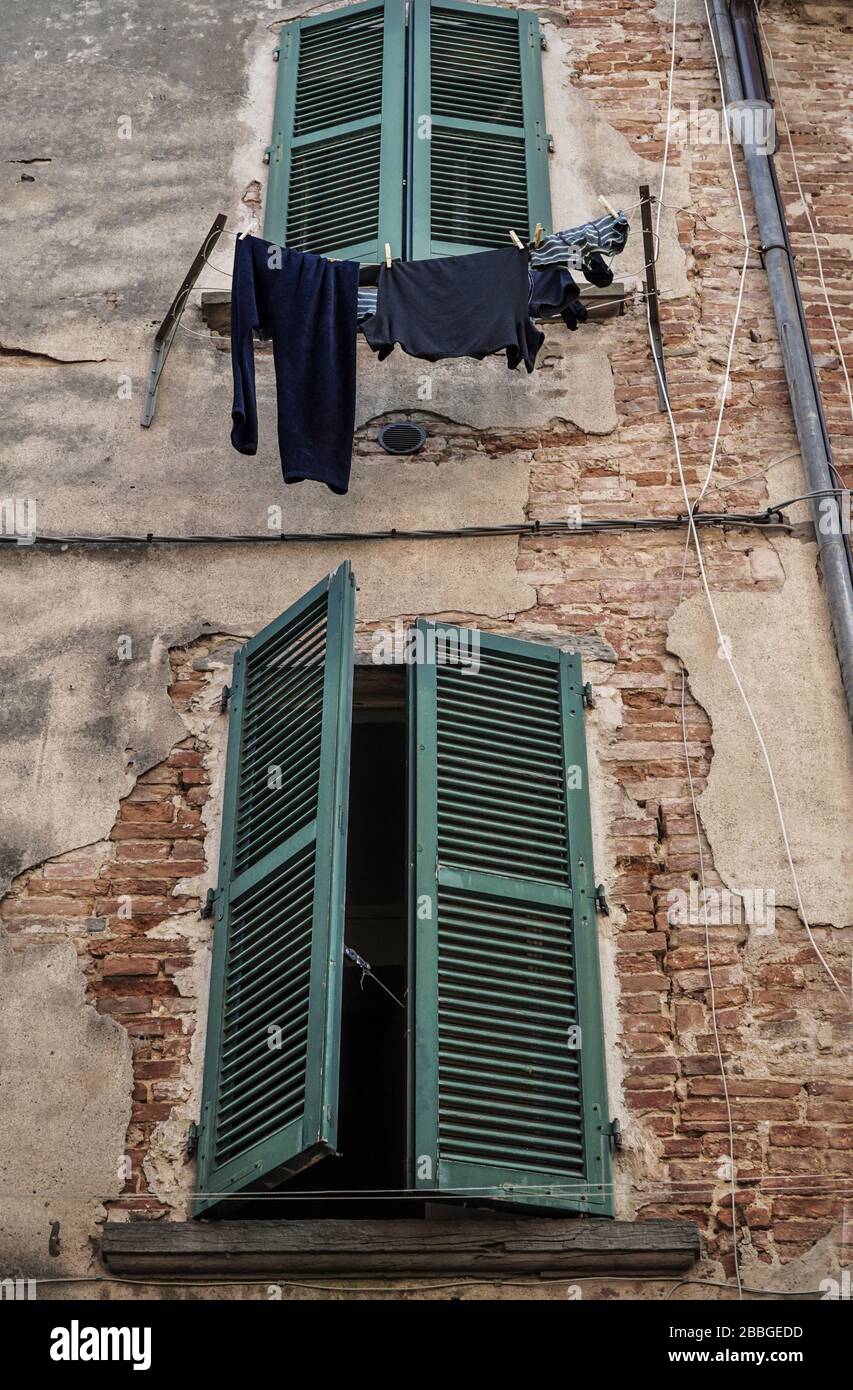 wet clothes hanged by green window blind of a building Stock Photo - Alamy