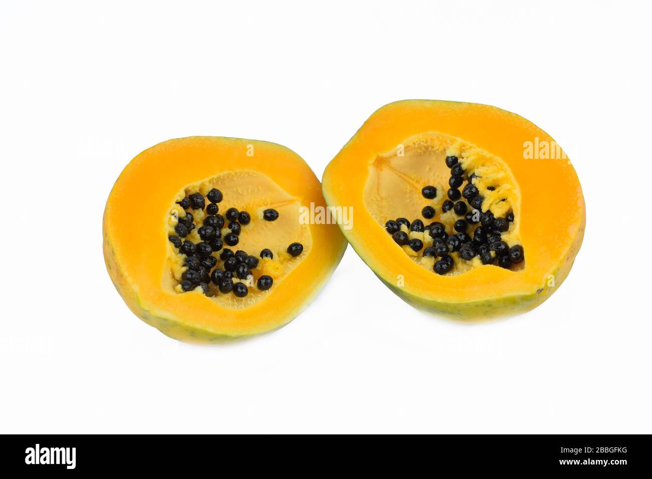 Two sliced pieces of fresh yellow ripe papaya fruit isolated before an ...