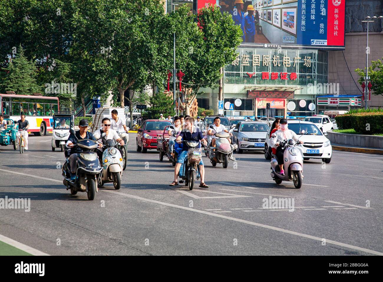Commuters on motorcycles and mopeds in traffic on street in Xian X'ian ...