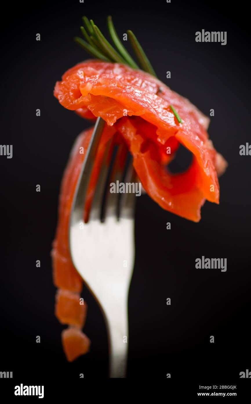slice of salty red fish on a fork, black background Stock Photo - Alamy