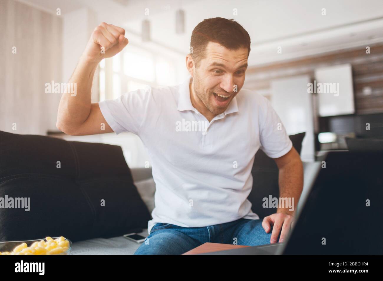 Young man watch tv in his own apartment. Emotional happy guy cheering ...