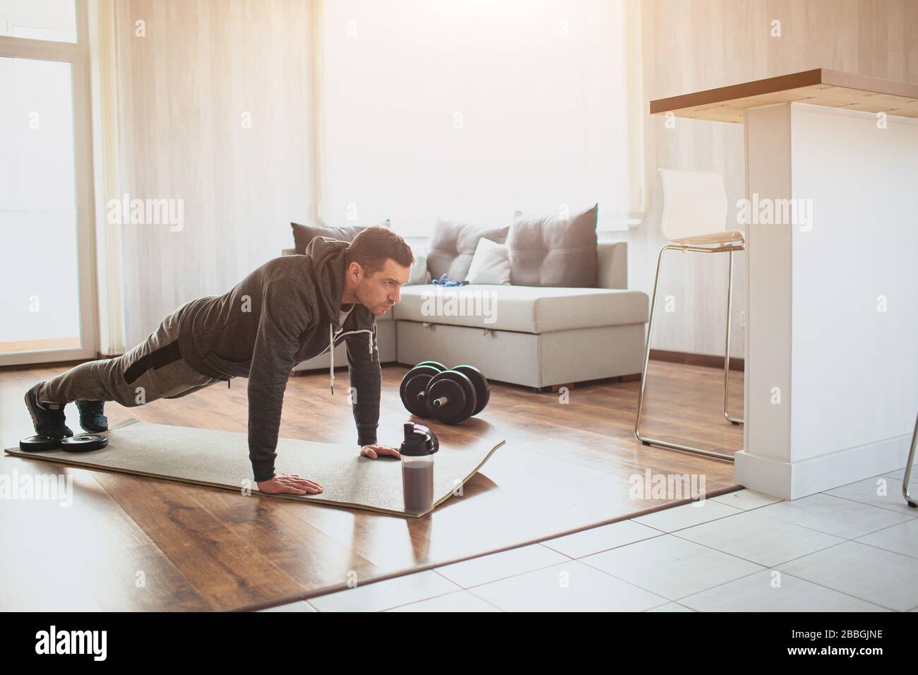 Young ordinary man go in for sport at home. Full size picture of ...