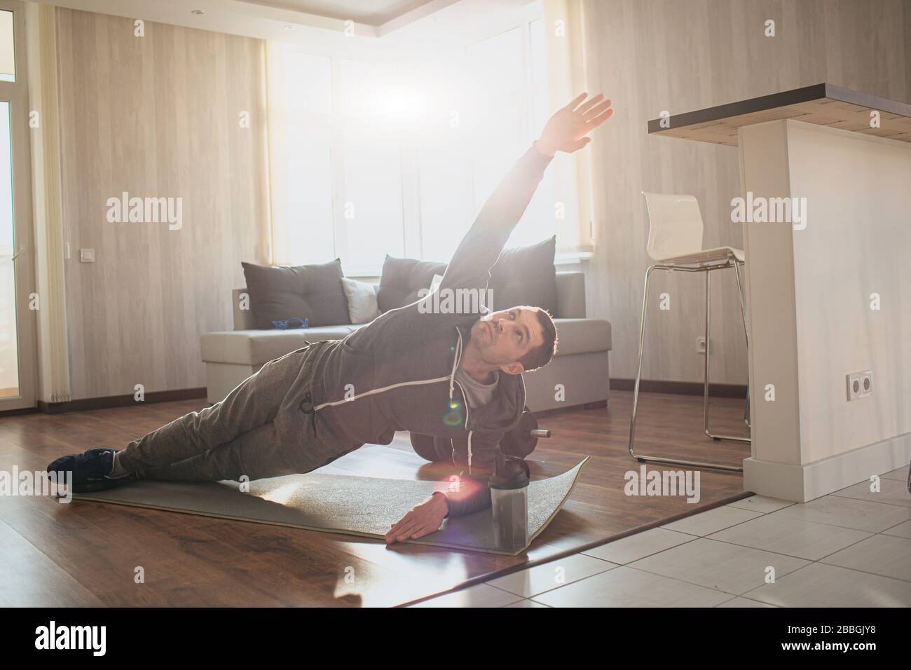 Young ordinary man go in for sport at home. Persistant freshman workout ...