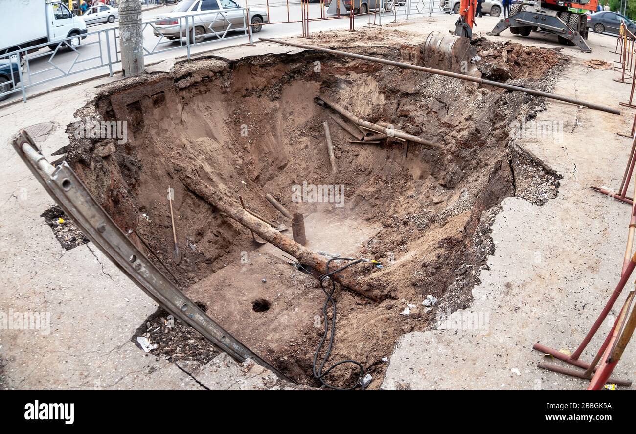 Construction works on rusty iron pipes at a depth of excavated trench ...