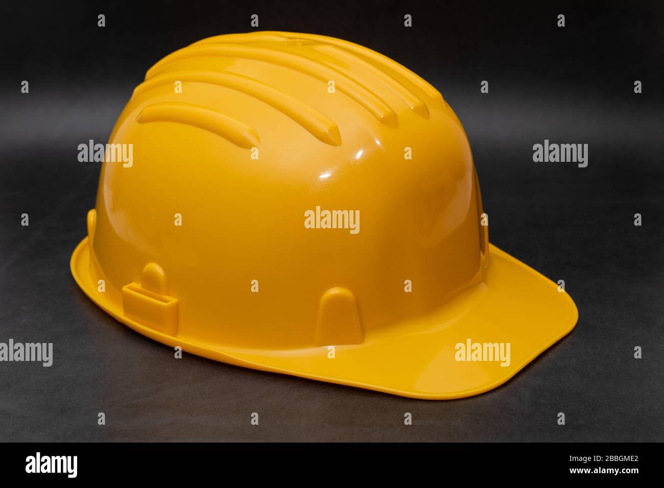 Professional yellow hard hat on dark background. Safety at work concept ...