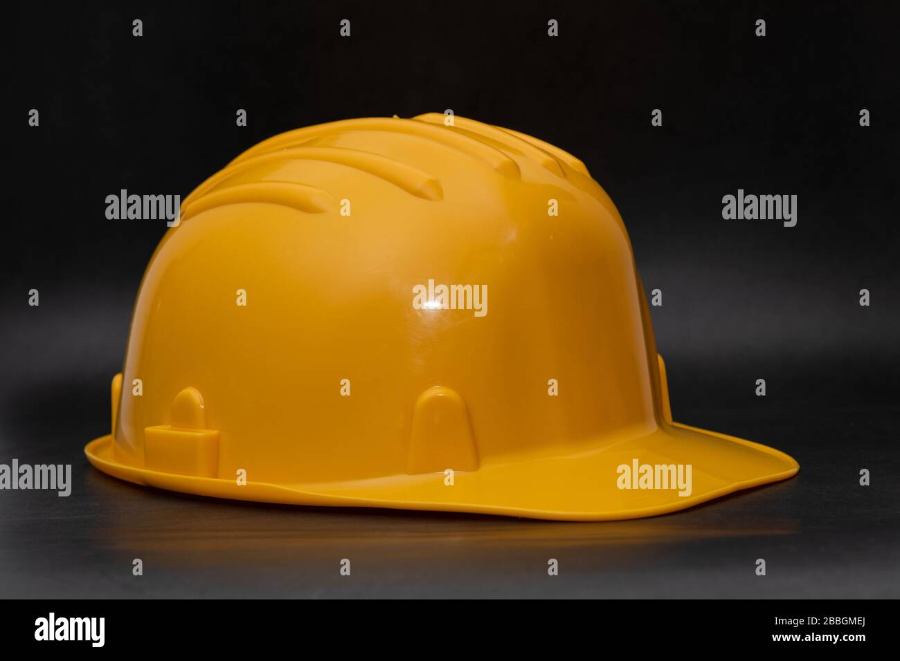 Professional yellow hard hat on dark background. Safety at work concept ...