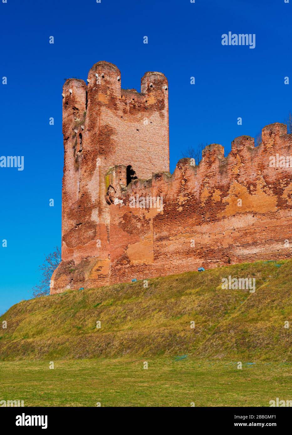 Medieval watchtower and wall made of red bricks against the clear blue ...