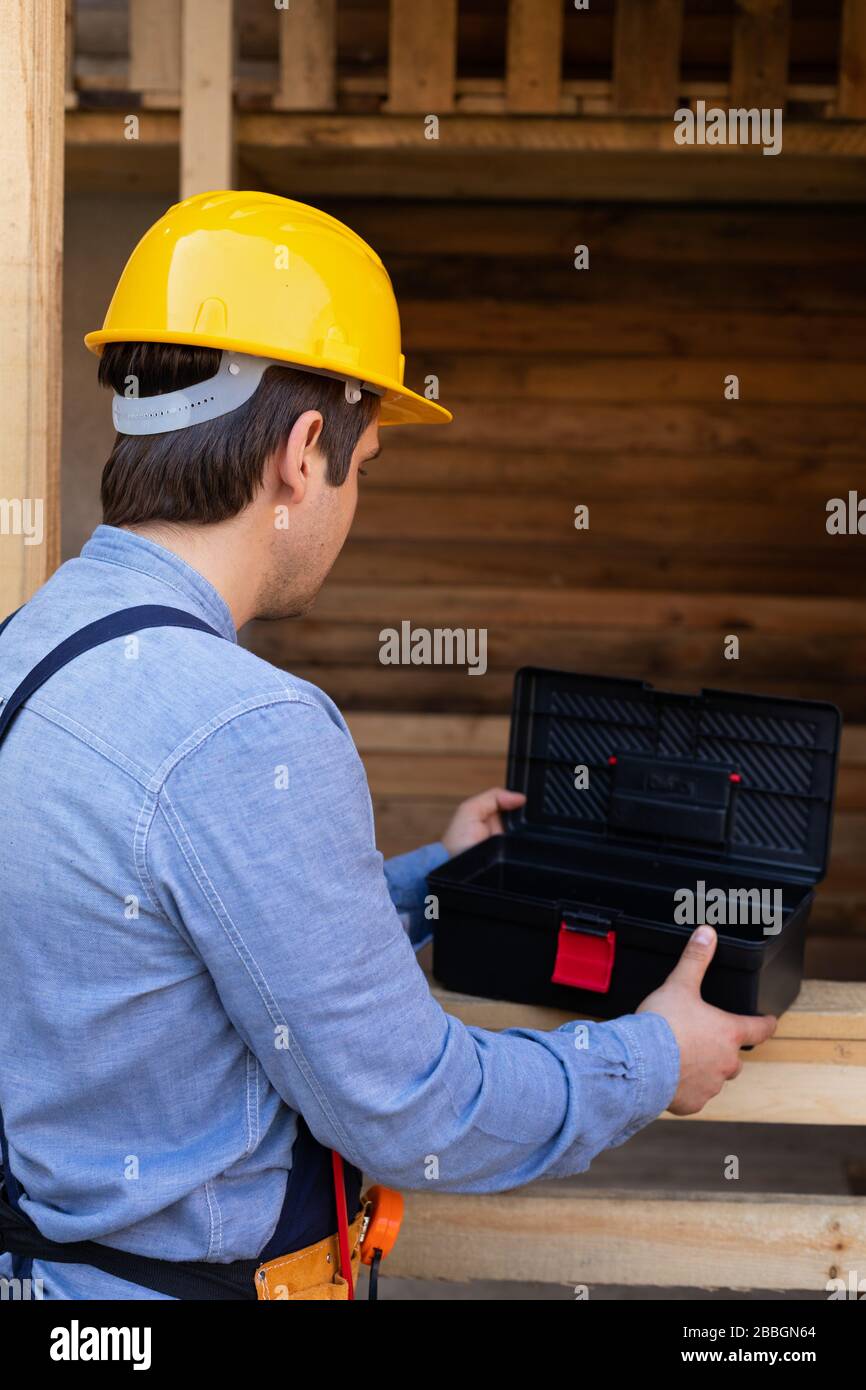 Back view of young carpenter with yellow hard hat and blue shirt ...