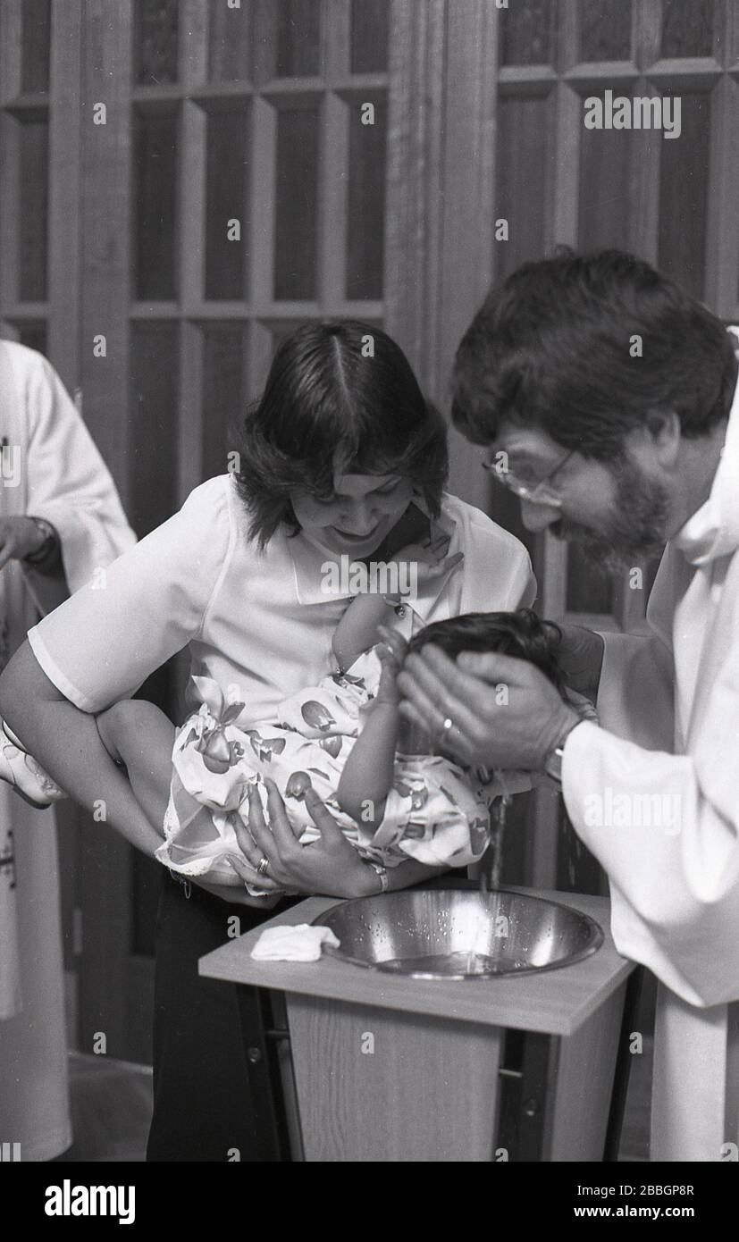 1970s, historical, Inside a church, a mother holding her small child as ...