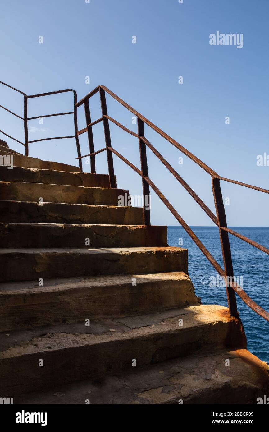 Stairs on a cliff at Neptuns Cave (Grotto di Nettuno). Rusted railing ...