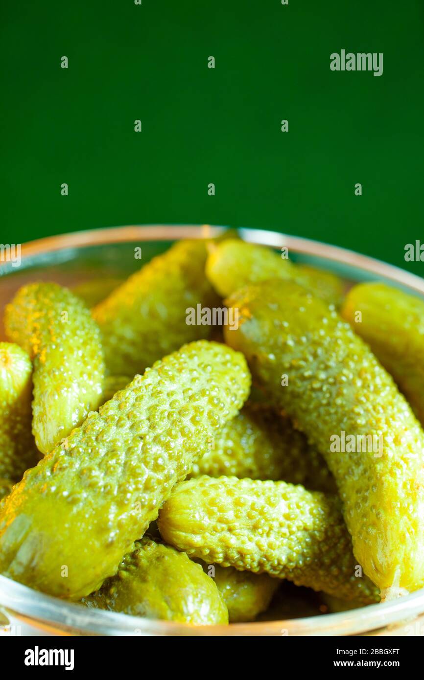 pickles in a glass oval jar on a wooden table with a green color ...