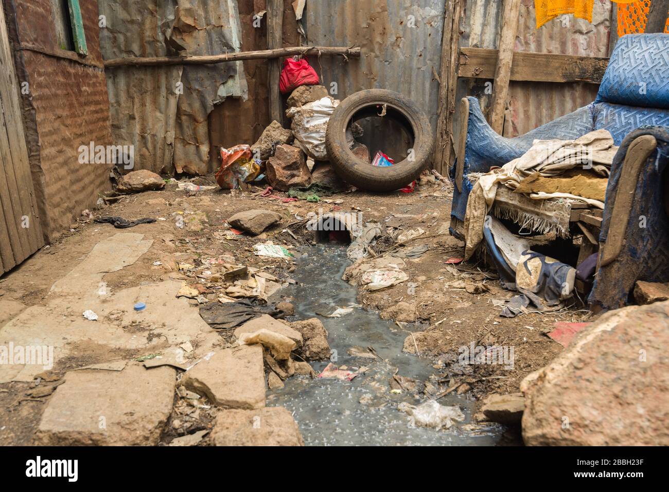 Open sewer running through small alley with metal slum shacks either ...