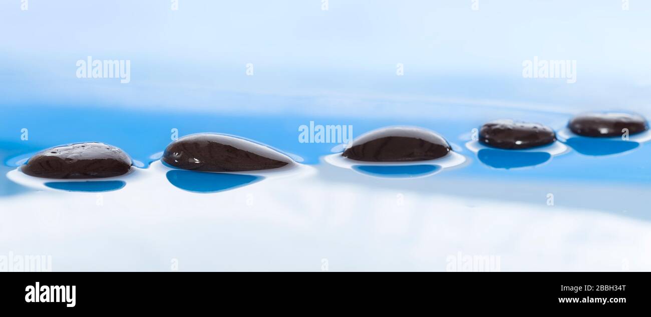Zen pebbles in blue water Stock Photo - Alamy