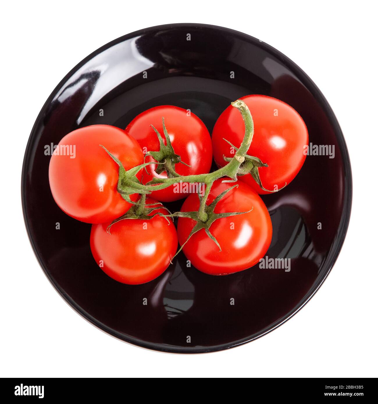 five tomatoes on a branch on a black plate isolated on white background ...