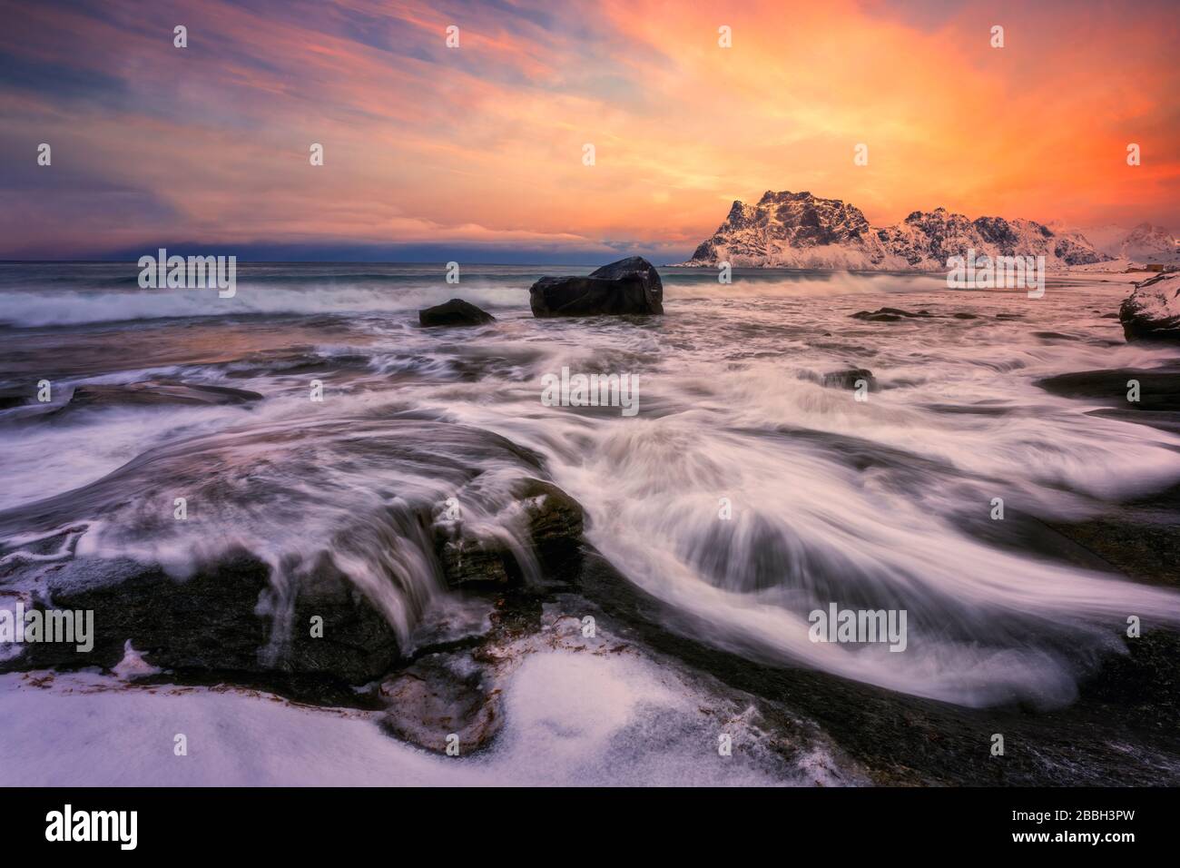 Dramatic sunset at beach, with waves washing over coastal rocks Stock ...