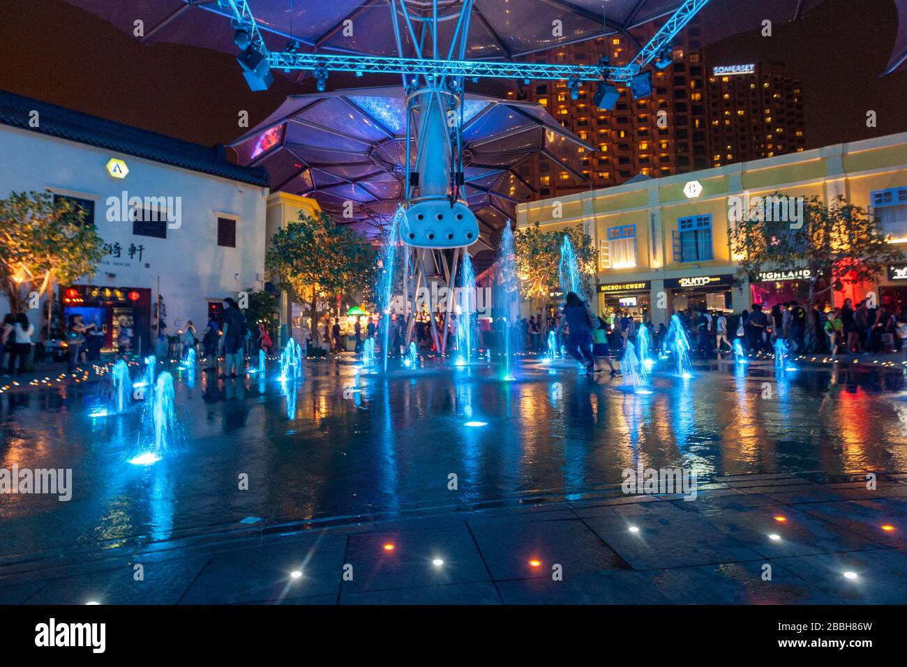 Children playing with a ground fountain in Clarke Quay, blocks of ...