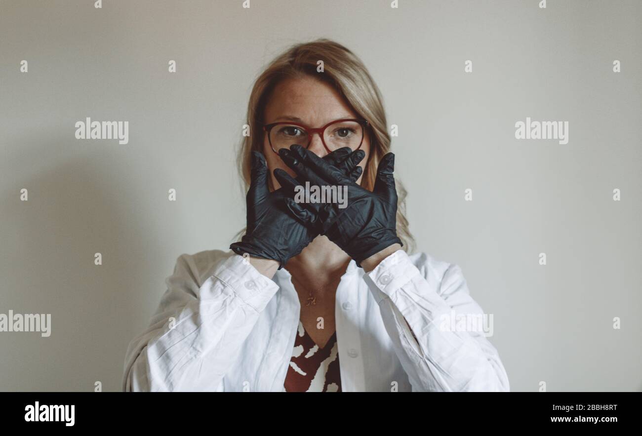 Young woman with black surgical gloved covering her face Stock Photo ...