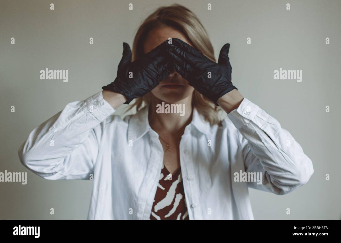 Young woman with black surgical gloved covering her face Stock Photo ...