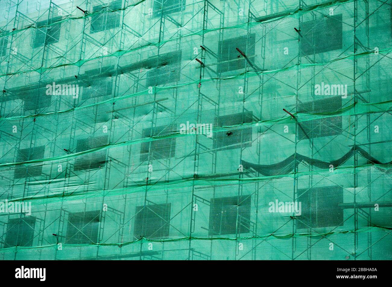 Building structure with green netting shade and scaffolding covered ...