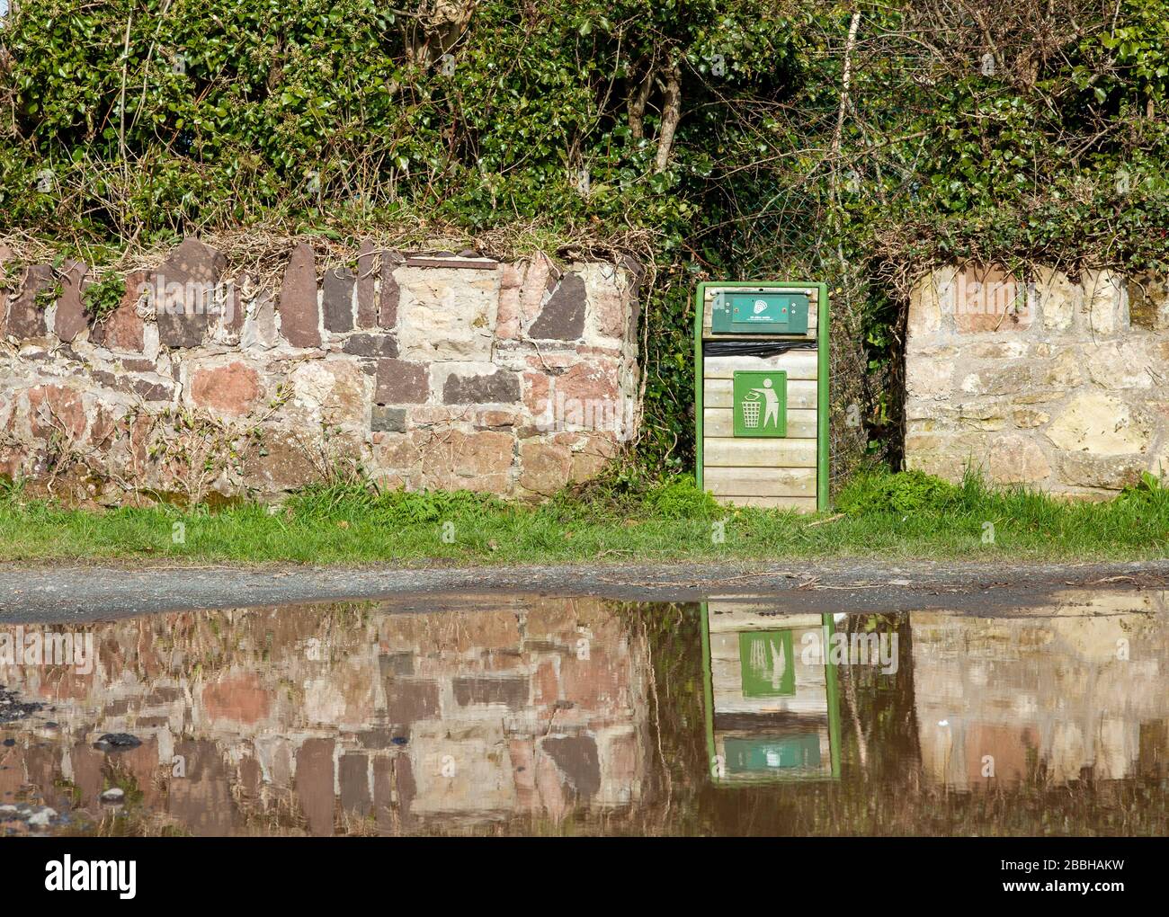 Waste bin in a stone wall with reflection in puddle Stock Photo - Alamy