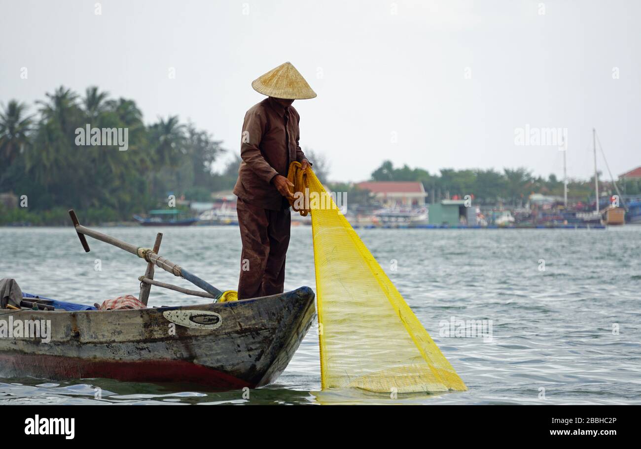 vietnamese fisherman on small boat fishing with fishnet Stock Photo - Alamy
