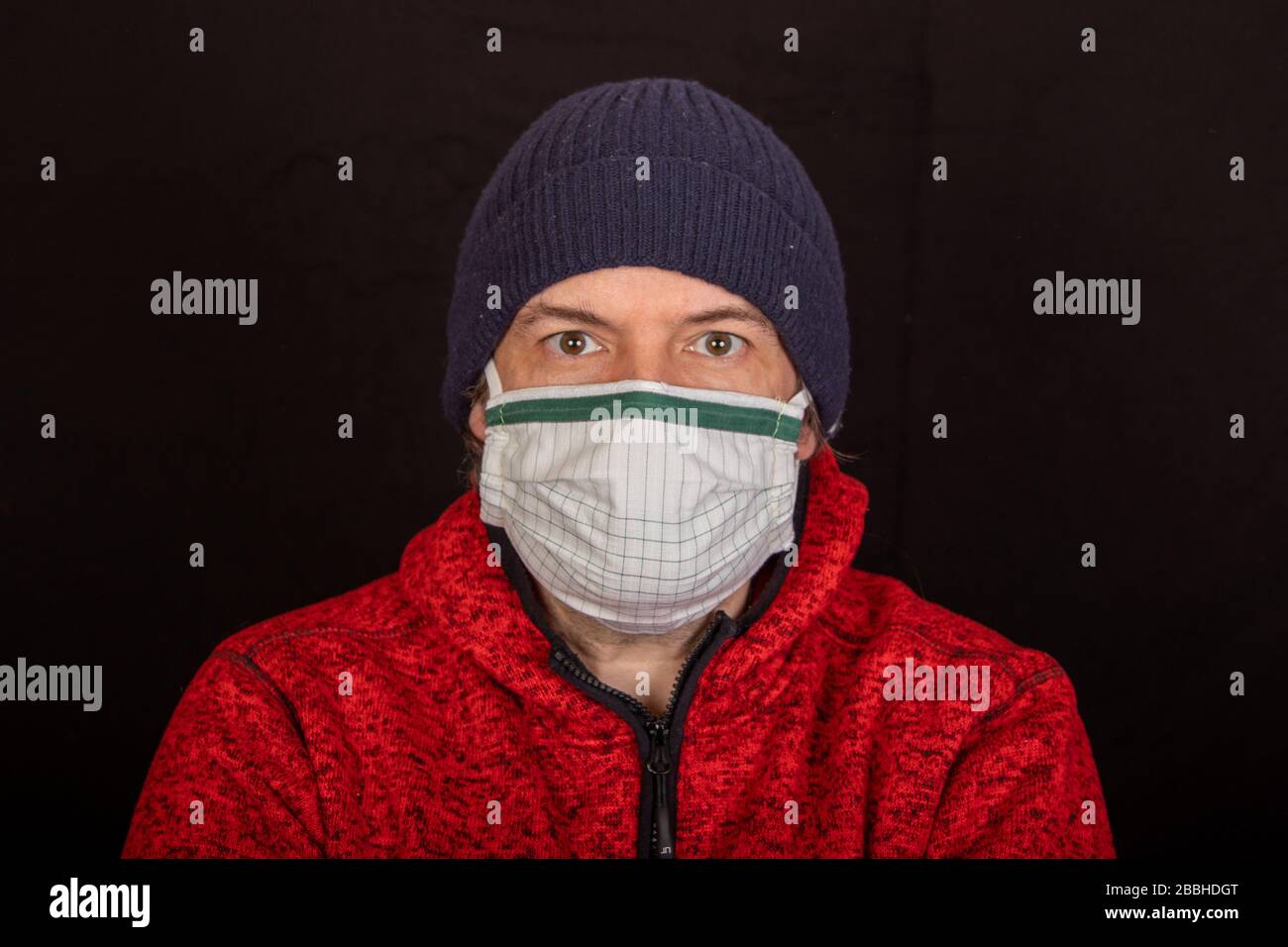 man wearing a selv made mouth protection and a blue woollen cap, black ...
