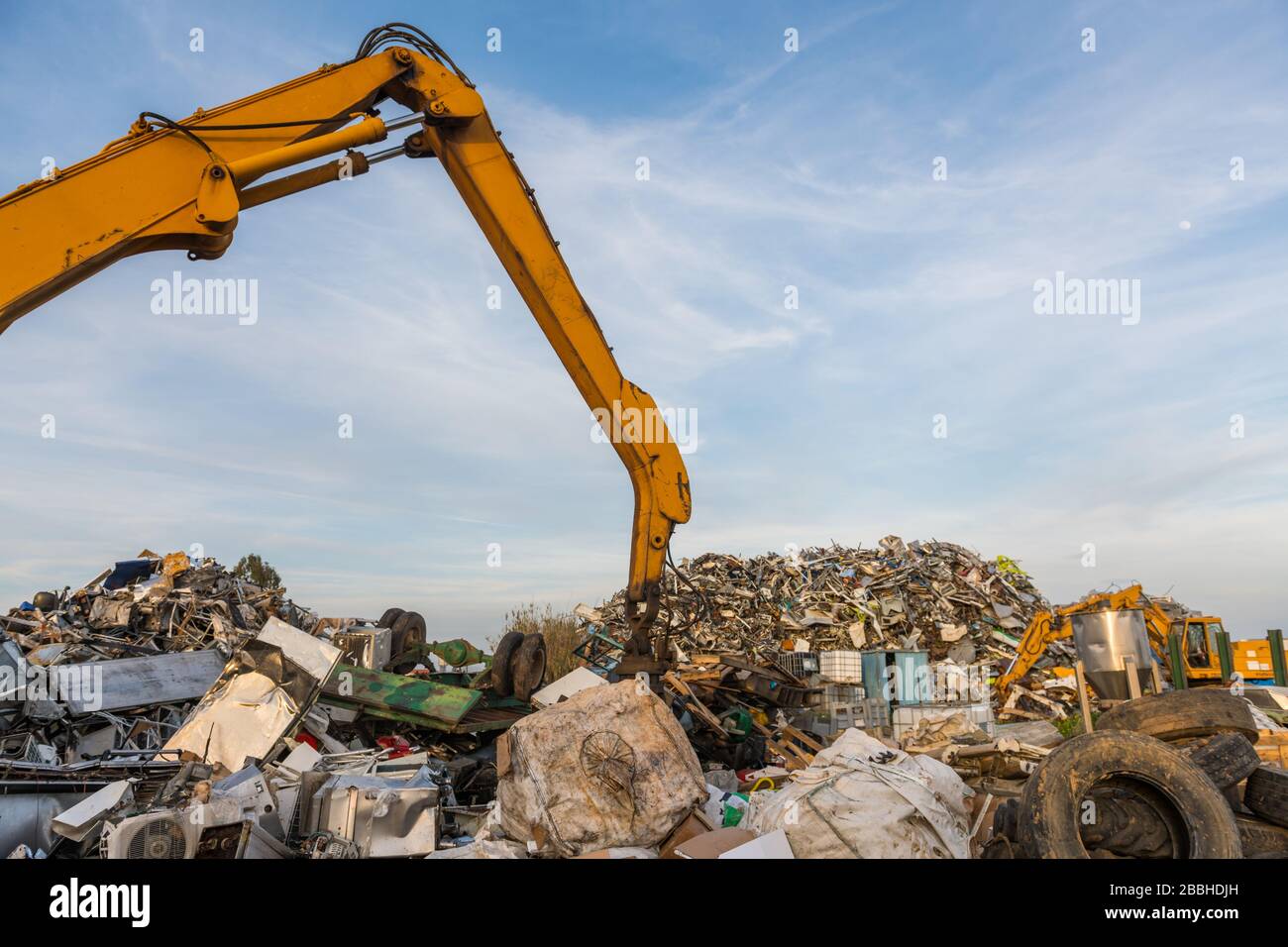 A crane moves pieces of metal through mountains of scrap metal in a ...
