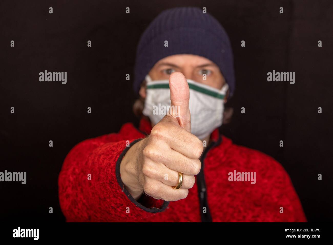 man wearing a selv made mouth protection and a blue woollen cap, thump ...