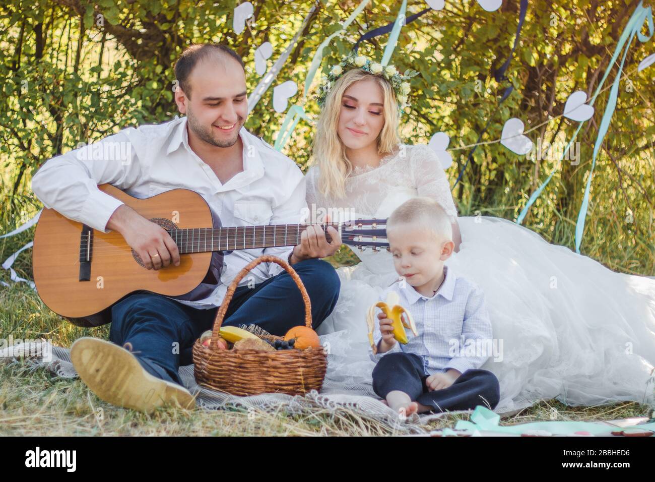 Picnic style outdoor wedding. Groom playing on guitar, young attractive ...