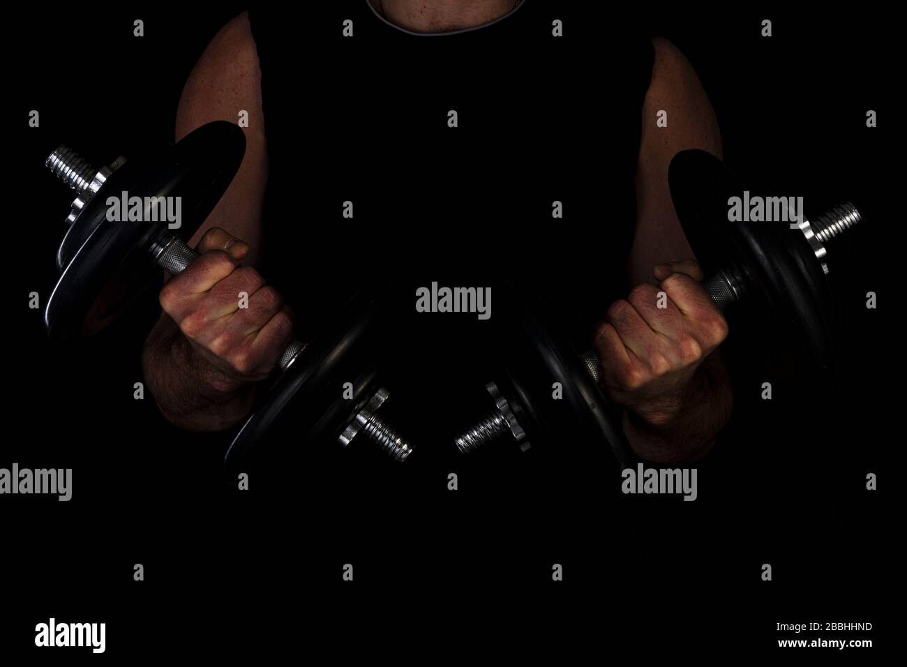 hand of a man with big biceps holds a steel type-setting dumbbell, low ...