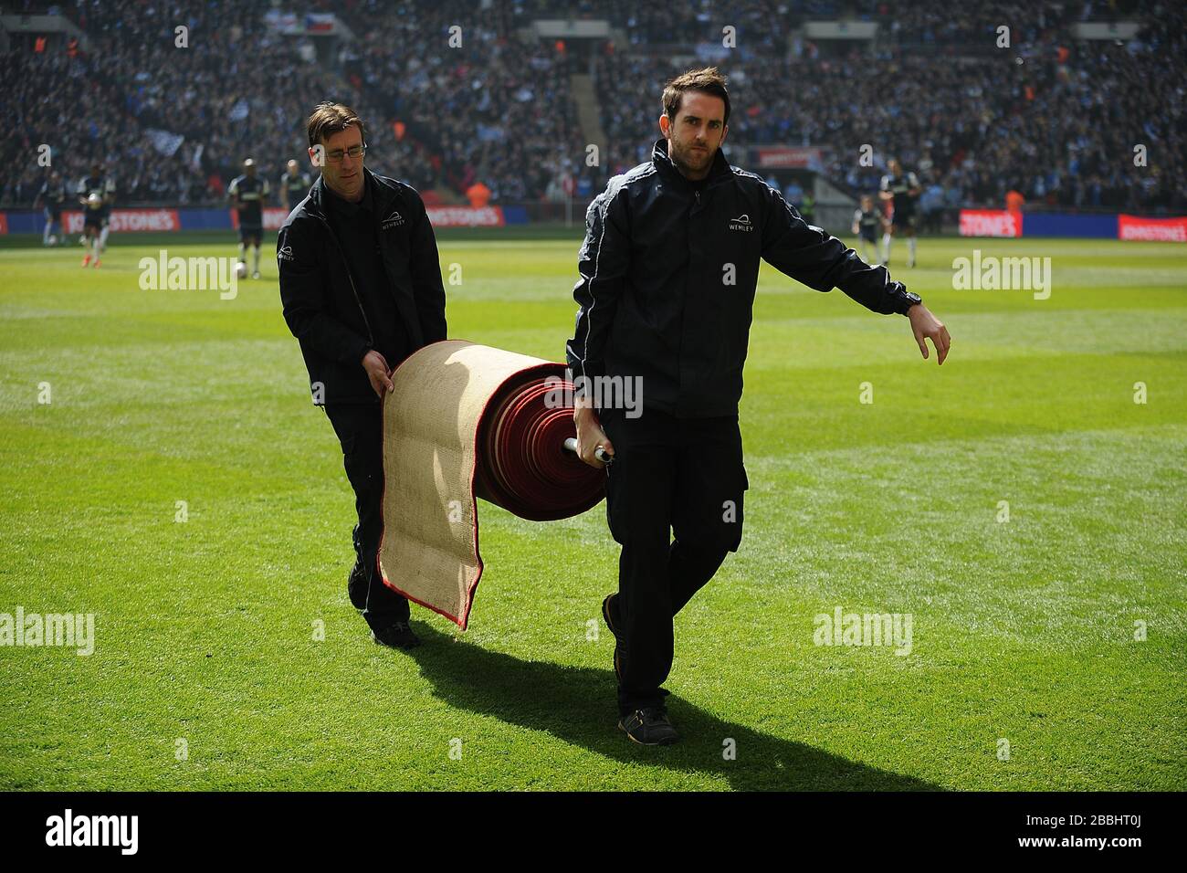 Groundstaff carry off the red carpet before kick off Stock Photo - Alamy
